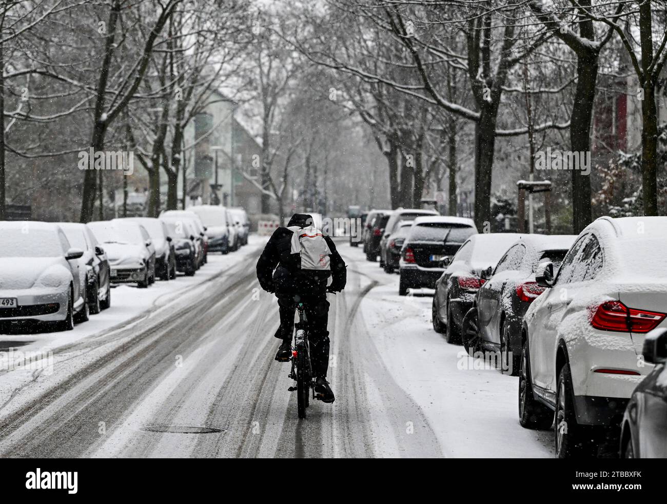 Berlin, Germany. 06 December 2023, Berlin: A cyclist rides on a snow ...