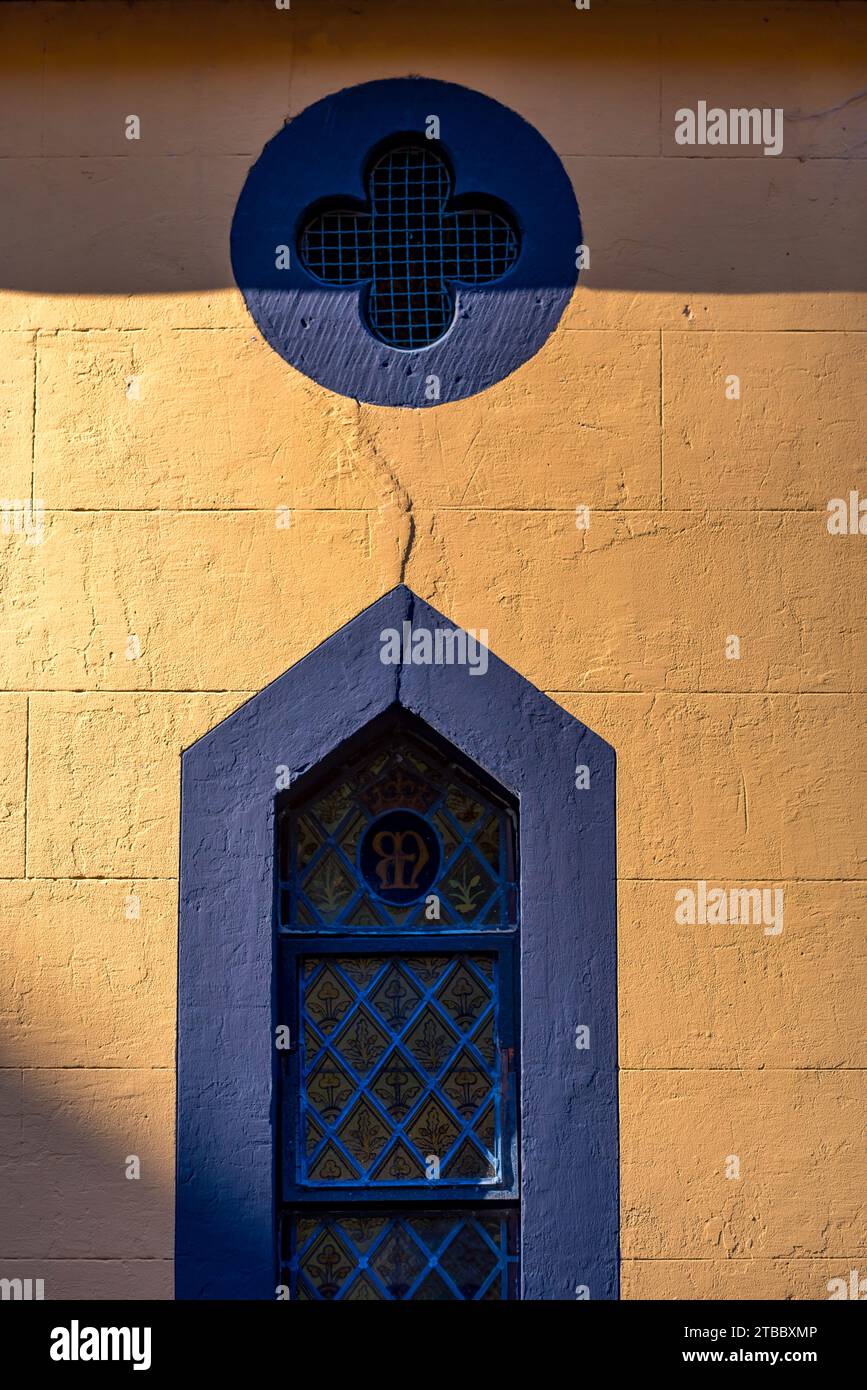 A deep set narrow arched window and a quatrefoil (clover leaf) window ...