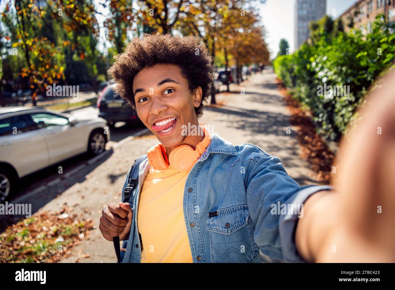 Photo of cheerful tricky guy dressed jeans shirt headphones tacking ...