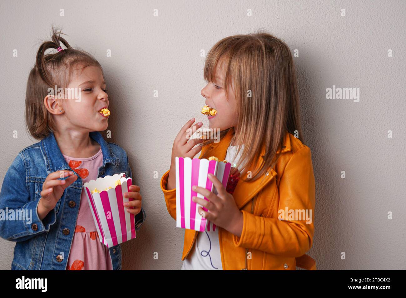 two happy little girls eating sweet popcorn Stock Photo - Alamy