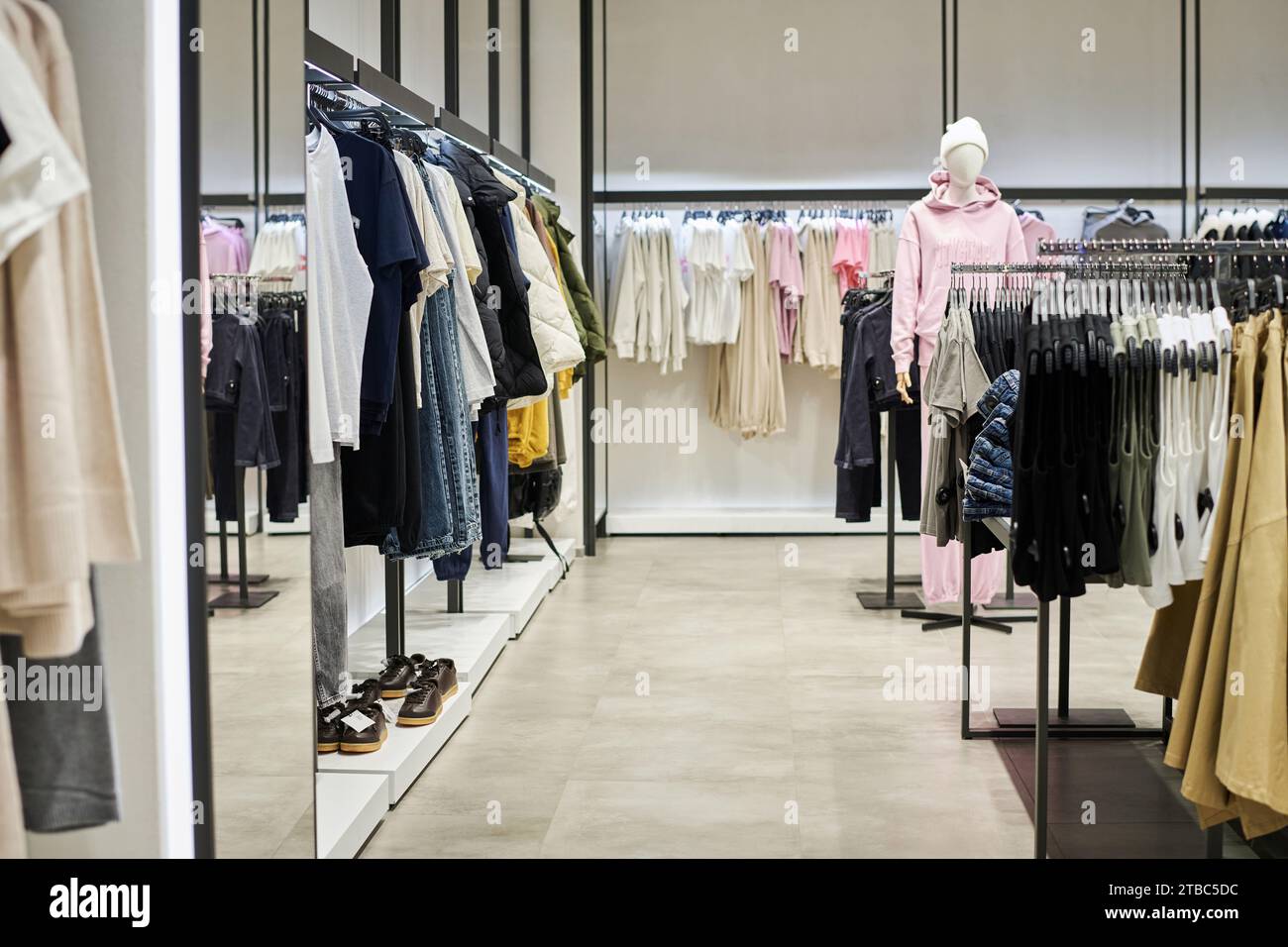 Wide shot of modern clothing store interior with garments for sale ...