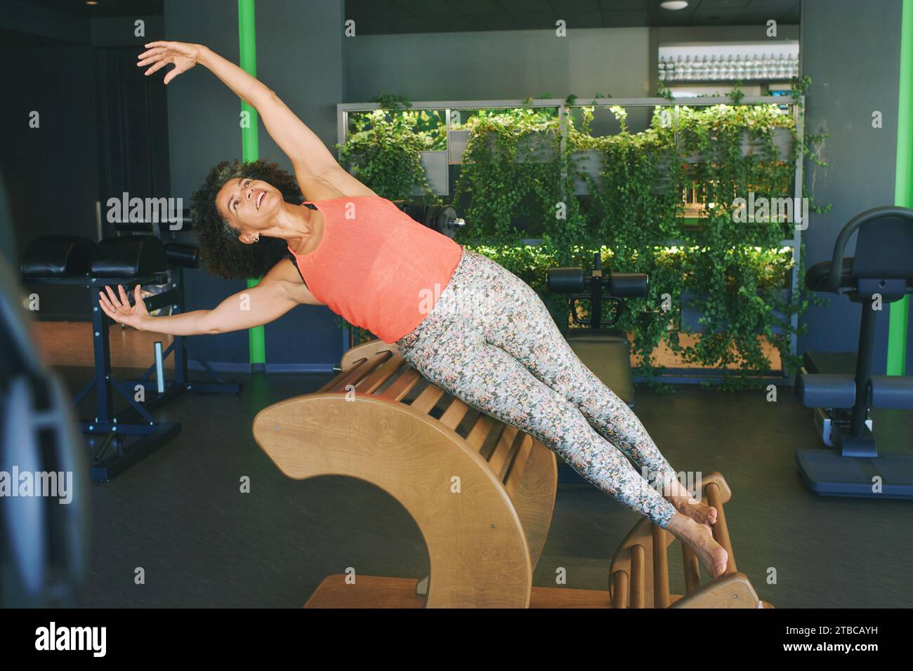 Mature 50 - 55 year old woman athlete stretching on wooden pilates ...