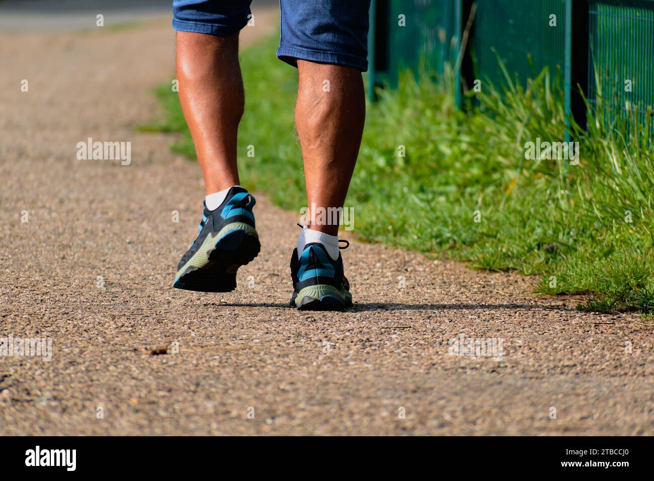 Man walking with sneakers on a path, close-up of his legs, sports ...