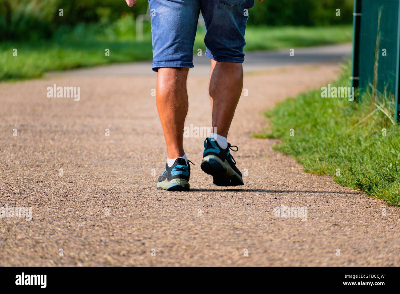 Man walking with sneakers on a path, close-up of his legs, sports ...