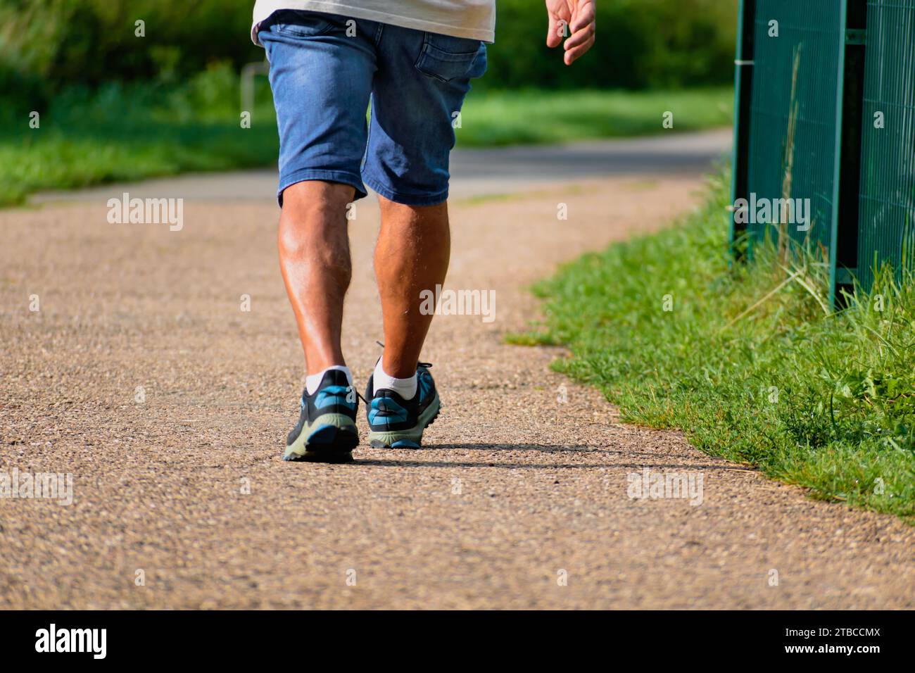 Man walking with sneakers on a path, close-up of his legs, sports ...
