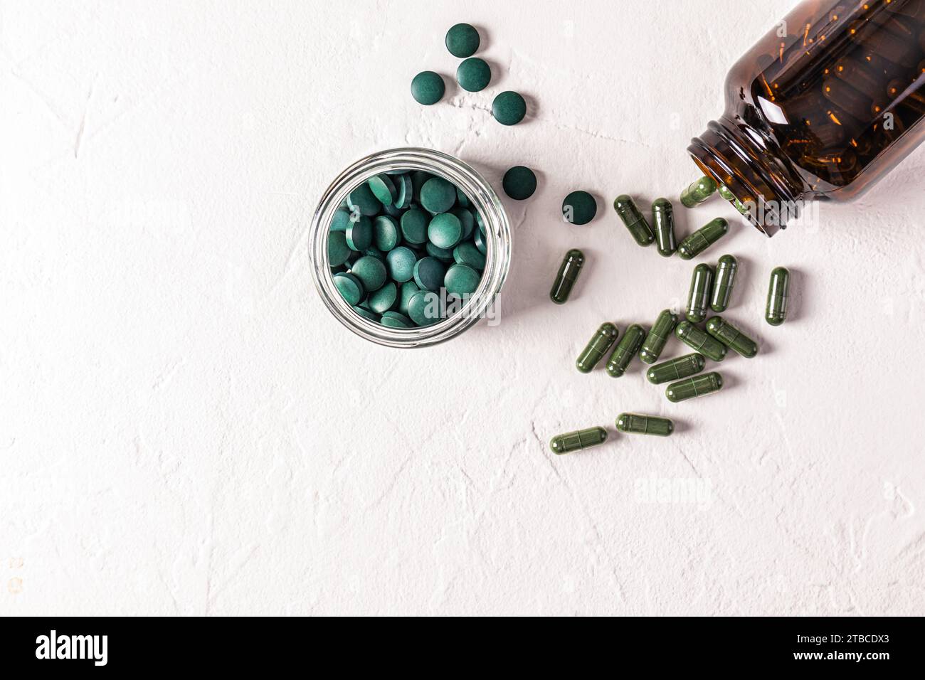 Round blue-green natural spirulina algae tablets in bowl on white ...