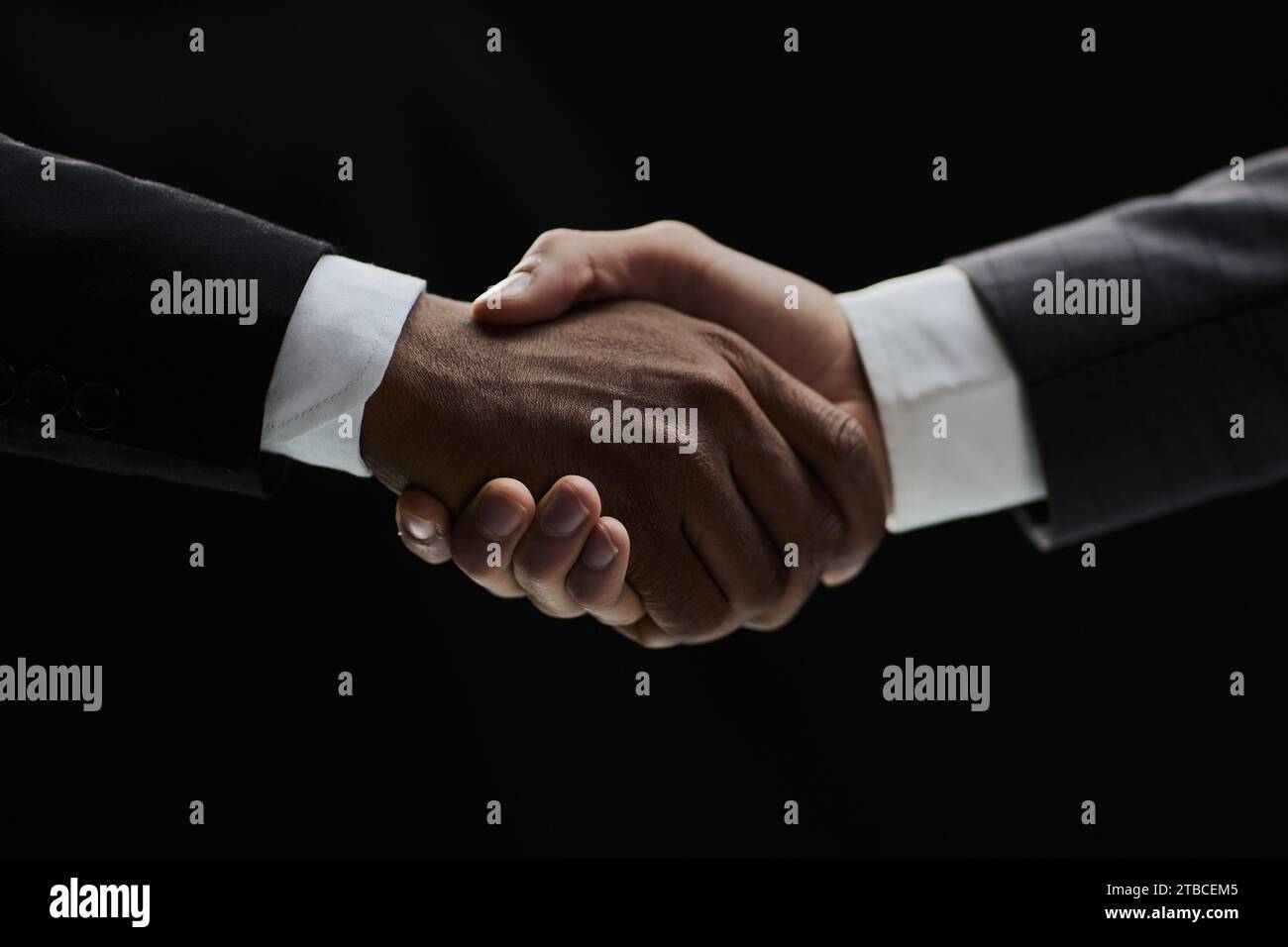 African man's hand shaking white man's hand on black background Stock ...