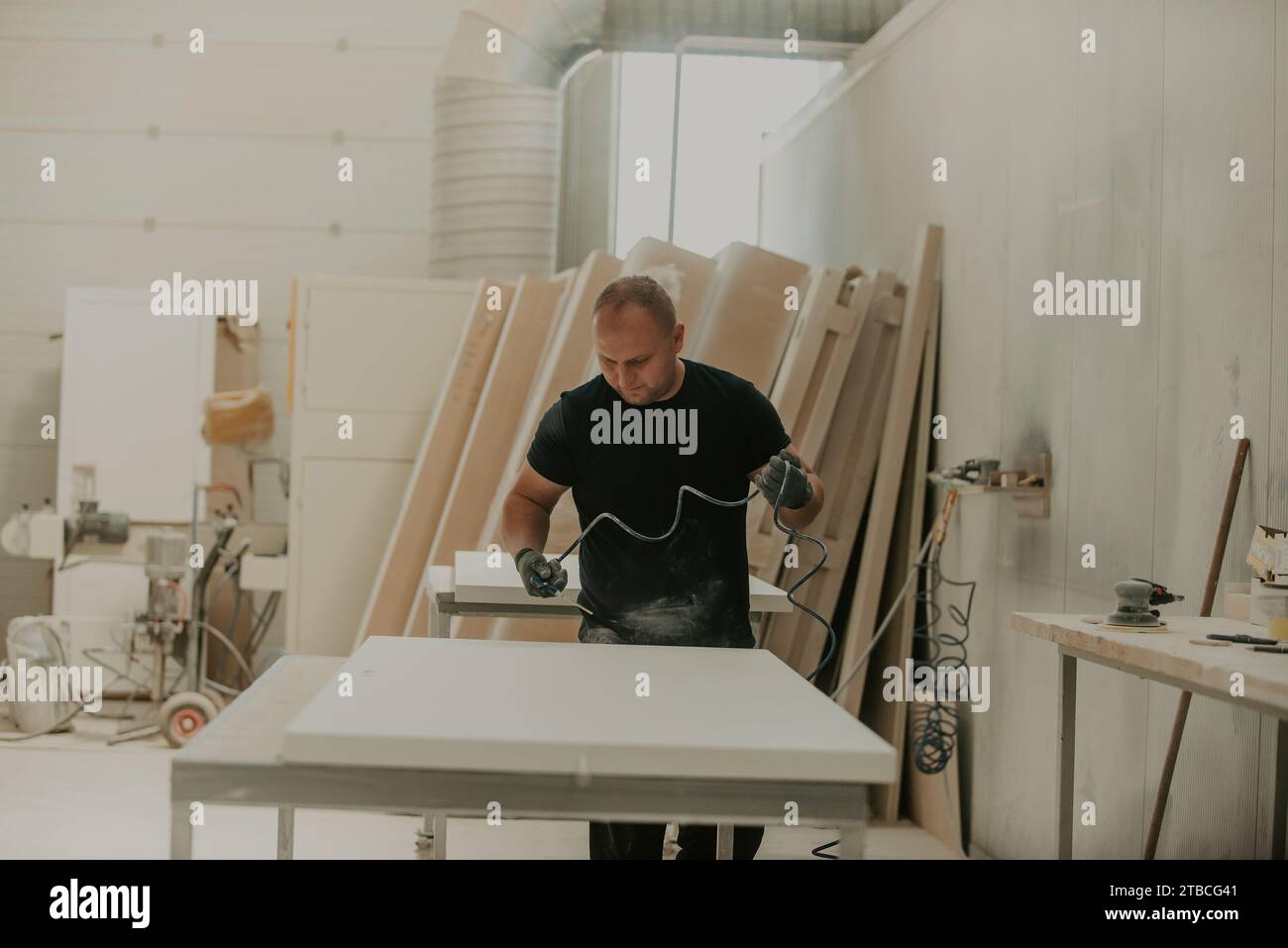 A dedicated worker in the woodworking industry employs compressed air ...