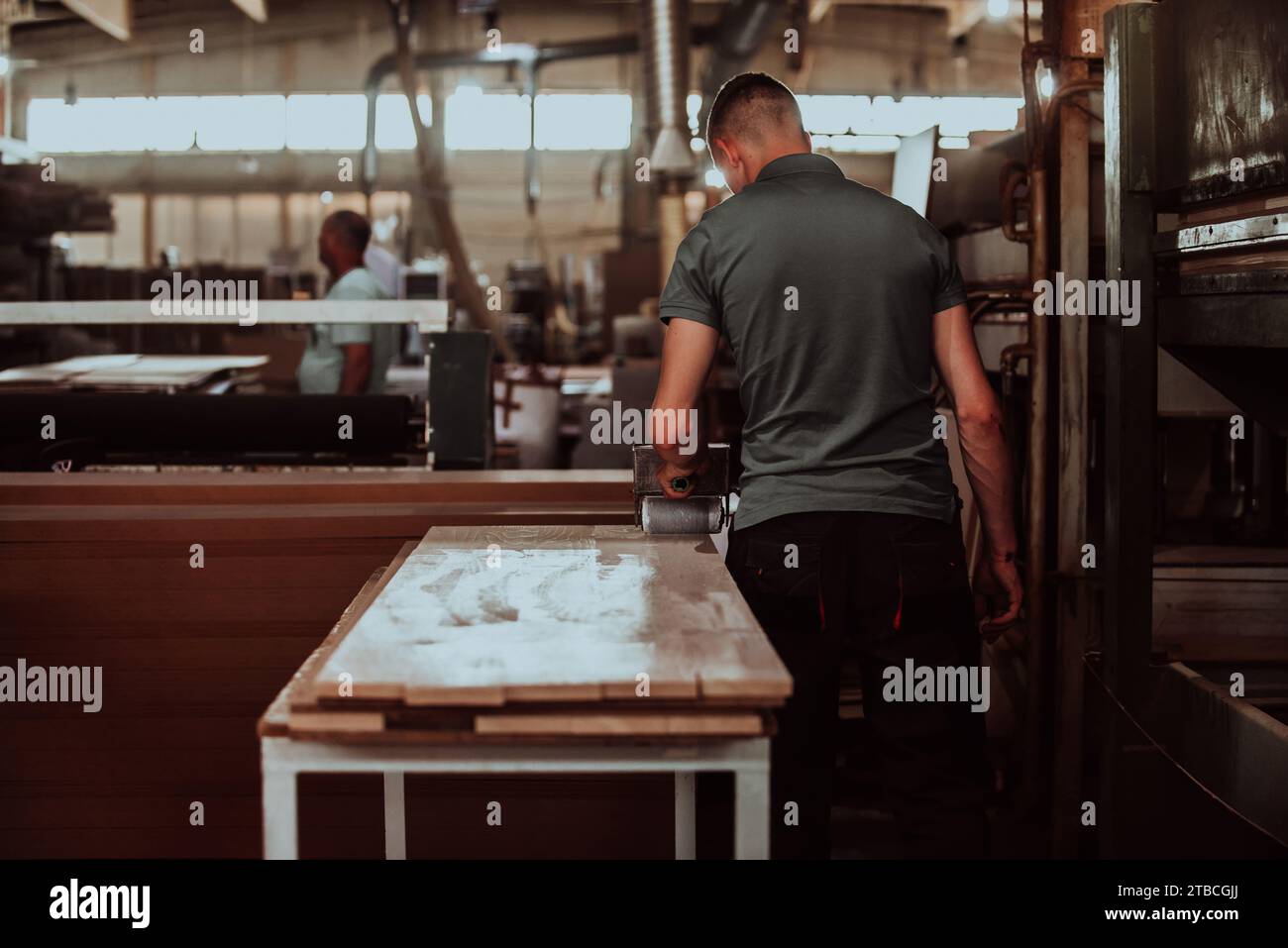 A dedicated worker in the woodworking industry meticulously paints ...