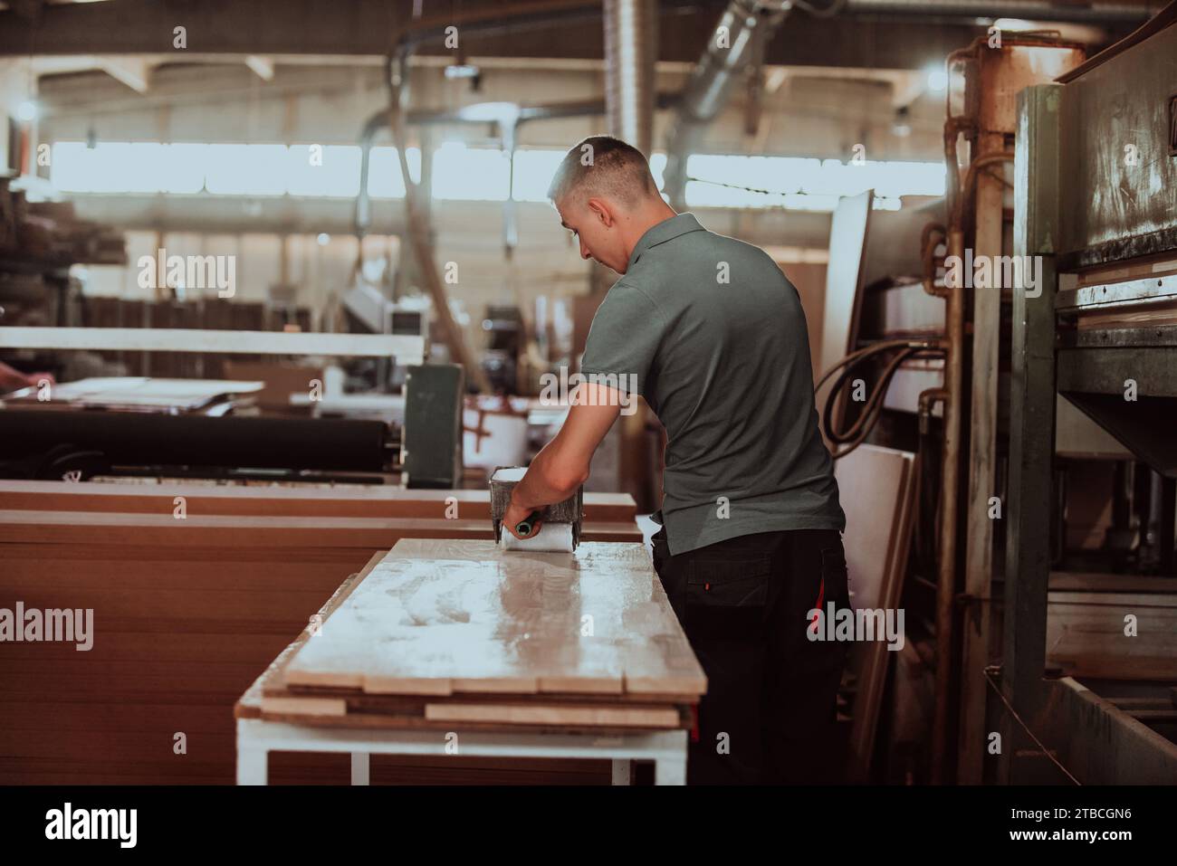 A dedicated worker in the woodworking industry meticulously paints ...
