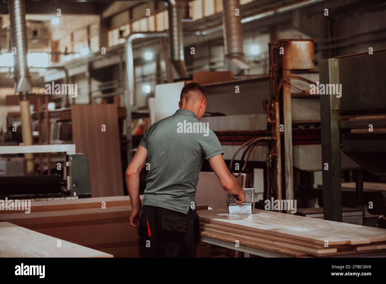 A dedicated worker in the woodworking industry meticulously paints ...