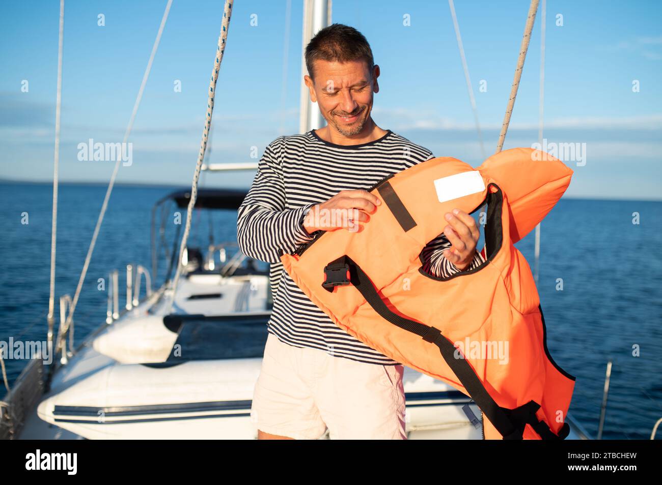 Man on a yacht putting on a life jacket Stock Photo - Alamy
