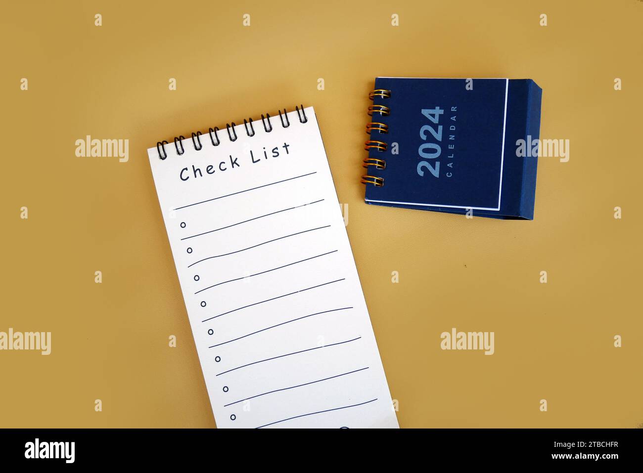 Top view. Checklist book with 2024 calendar and green plant. New Year 2024 goals, resolutions ...