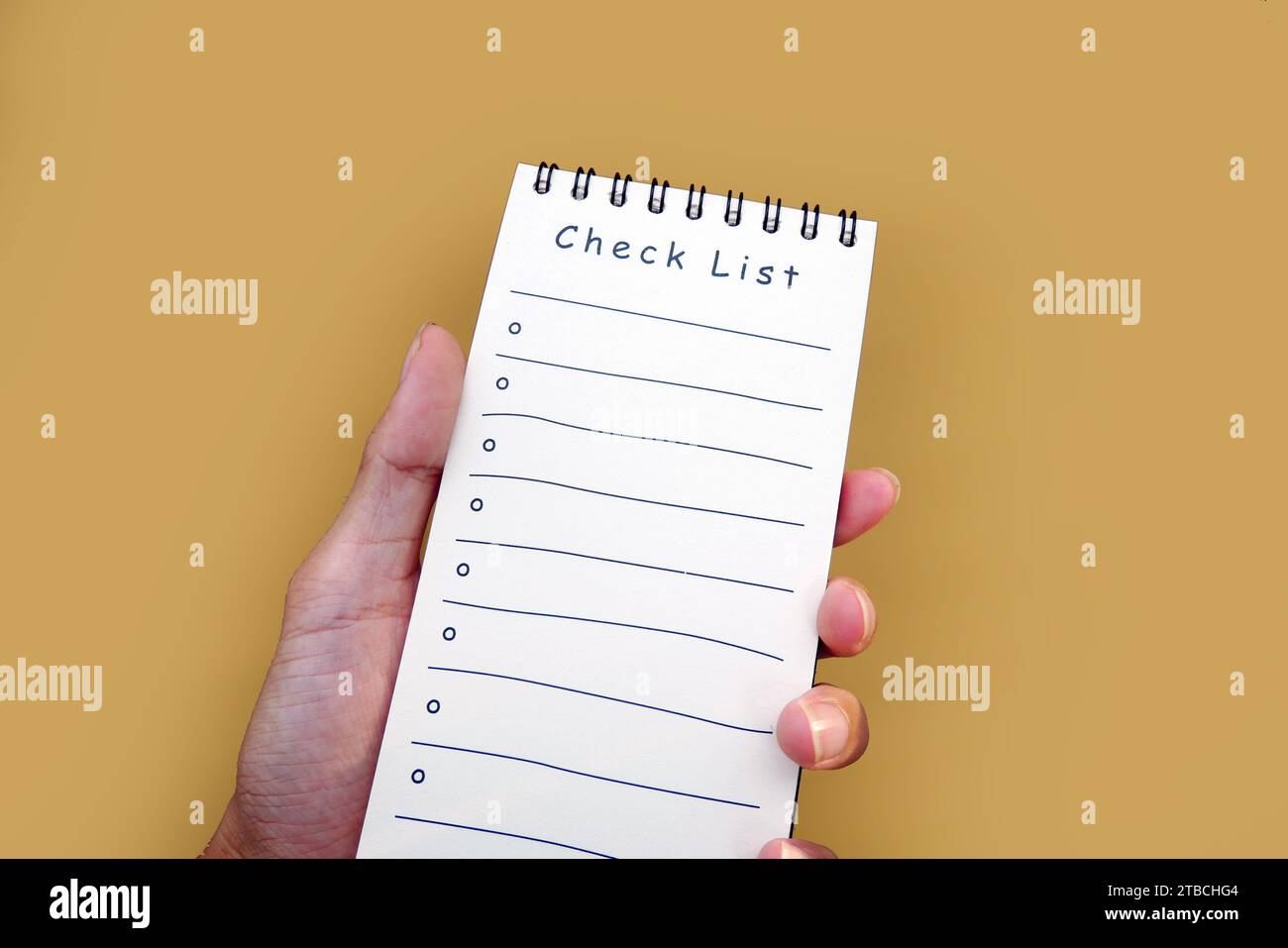 A hand holding the checklist book on a ginger background. New Year 2024 ...