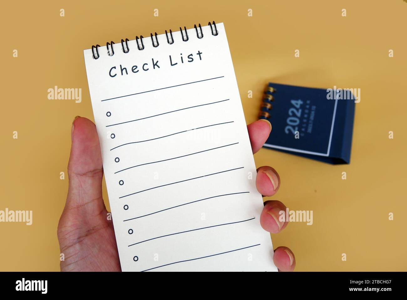 Top view. Checklist book with 2024 calendar and green plant. New Year 2024 goals, resolutions ...