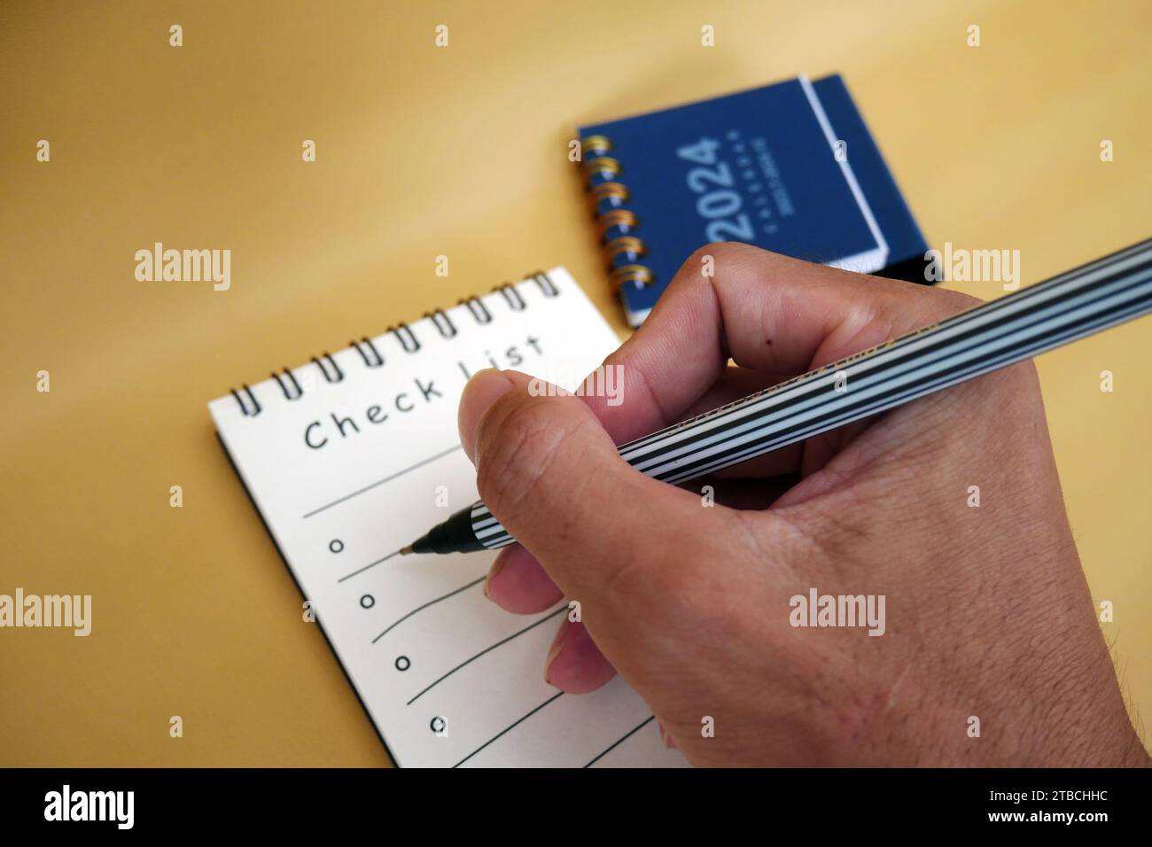 Top view. Checklist book with 2024 calendar and green plant. New Year ...