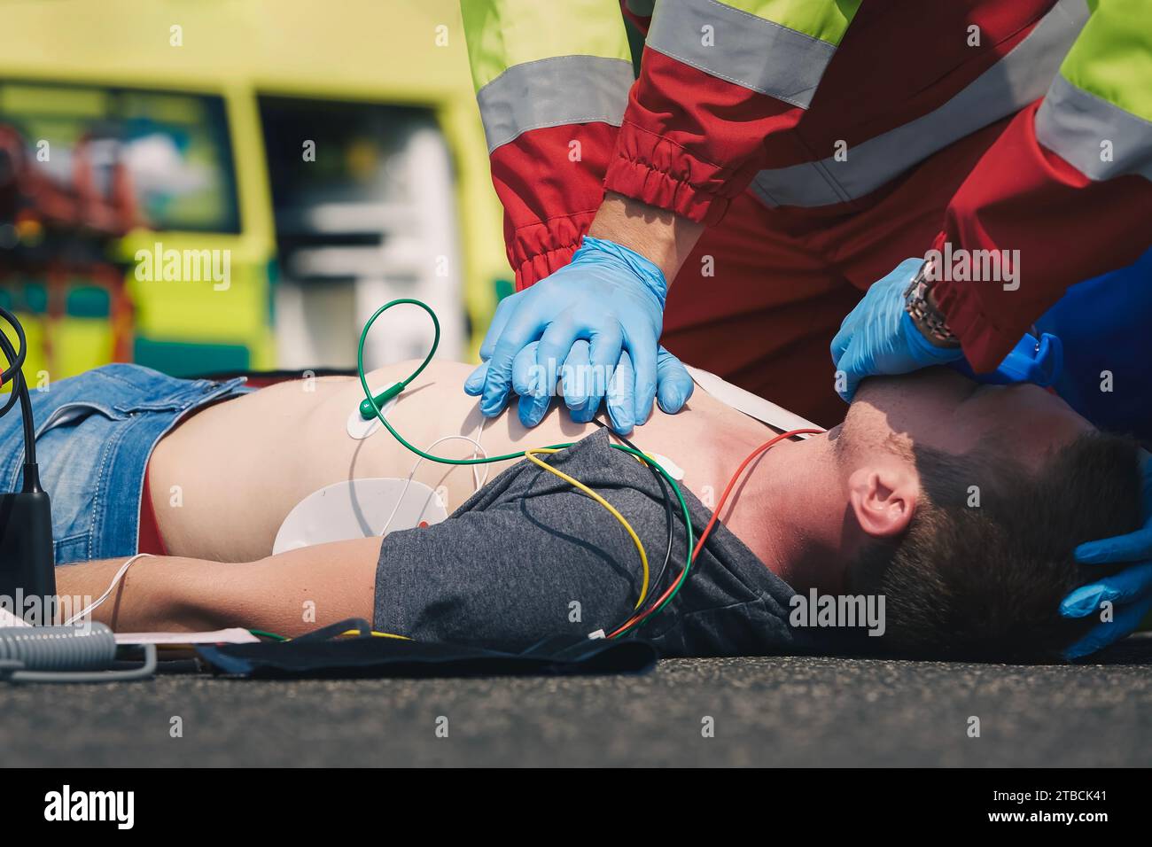 Hands of paramedic and doctor during resuscitation on road against ambulance car. Patient and ...