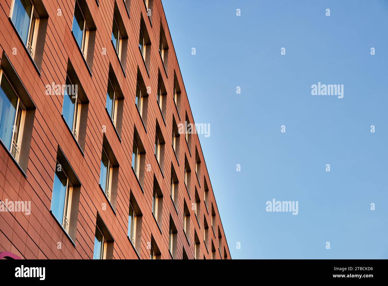Modern orange bricked facade with windows against the sky is an example ...