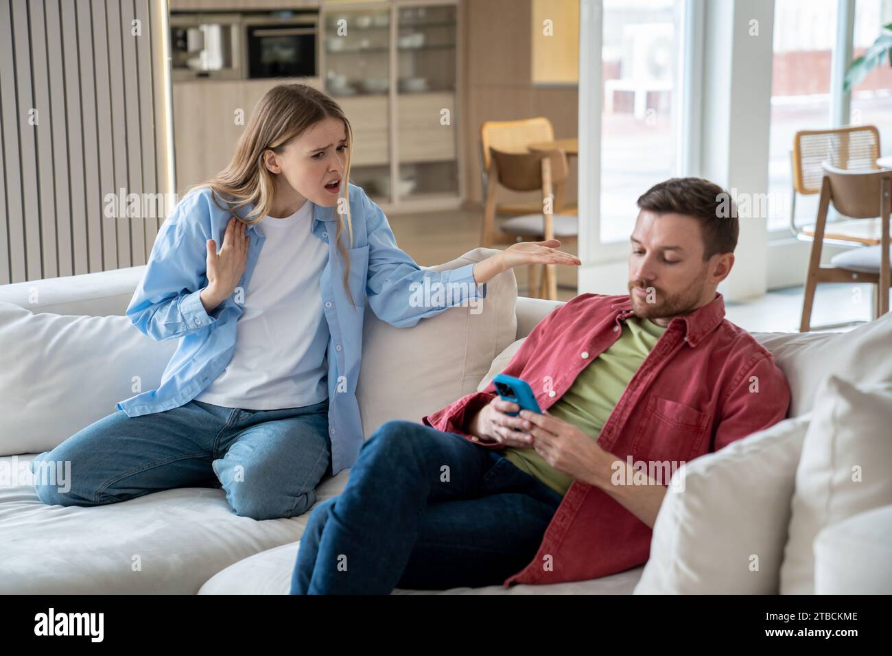 Offended wife reproaching uncaring husband in doing nothing, sitting ...