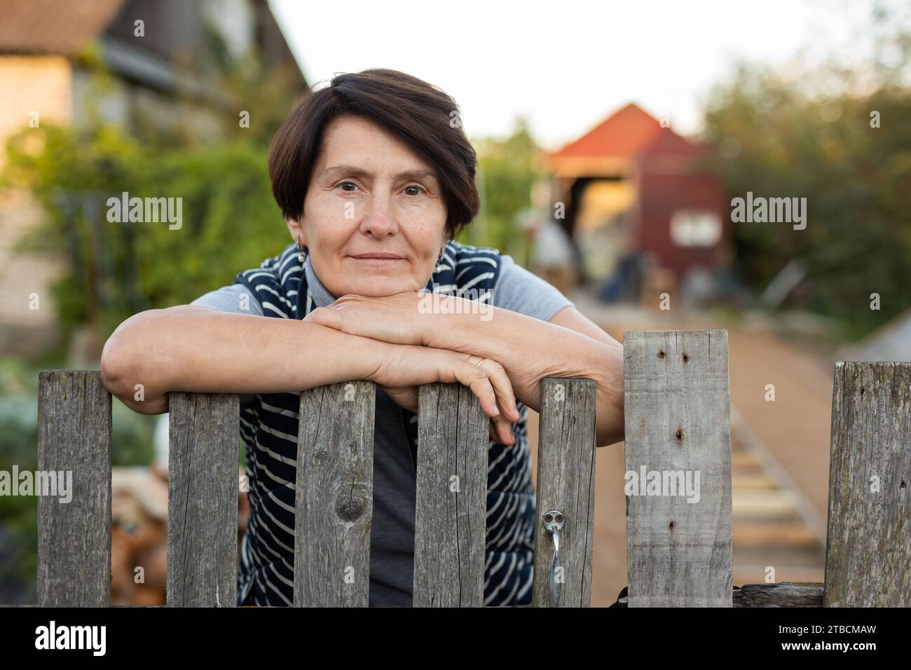 Mature woman standing relaxed near fence in backyard smiling Stock ... Mature woman standing relaxed near fence in backyard smiling Stock ...