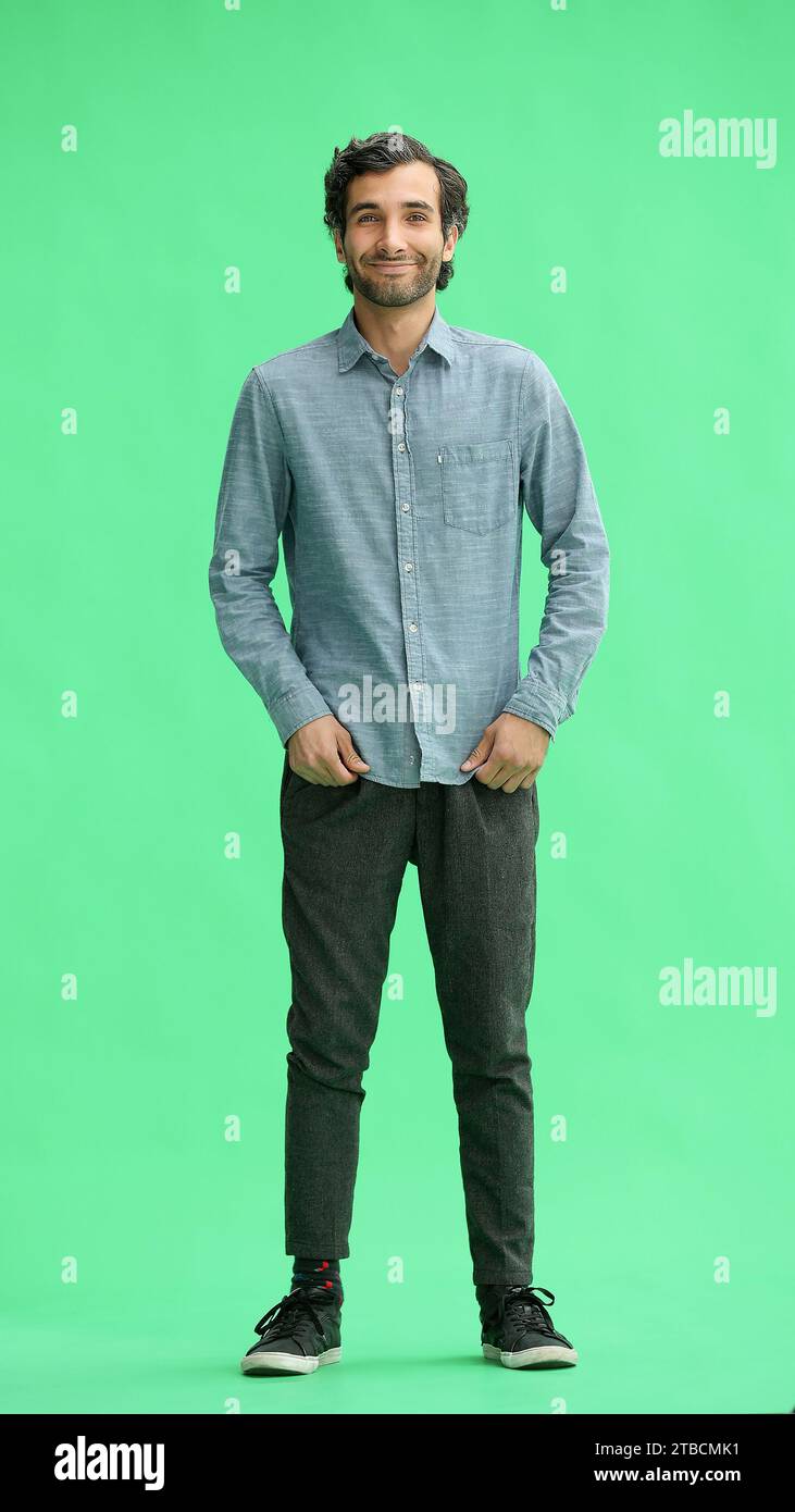 full-length portrait of a young man. standing isolated on green ...