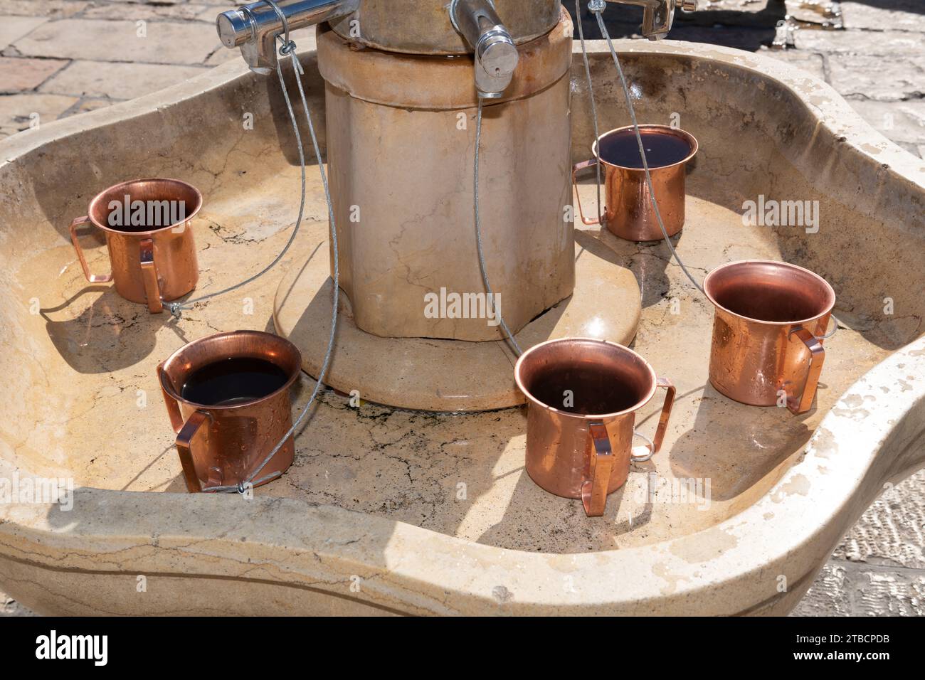 Copper natla or Jewish ritual hand washing cups lie in a marble sink ...