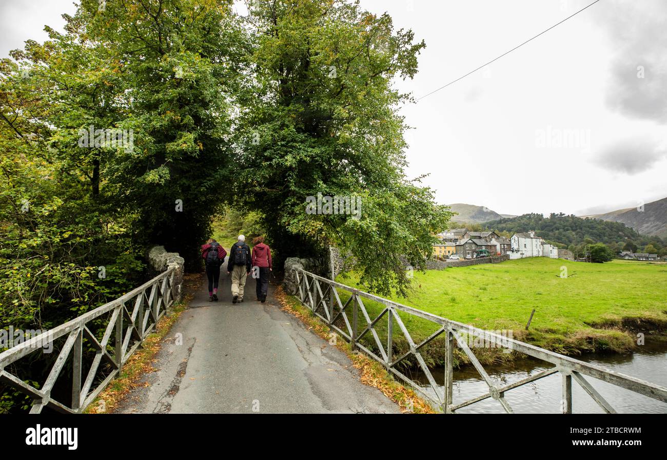 Walkers crossing a bridge over Goldrill Beck, Patterdale, Lake District ...