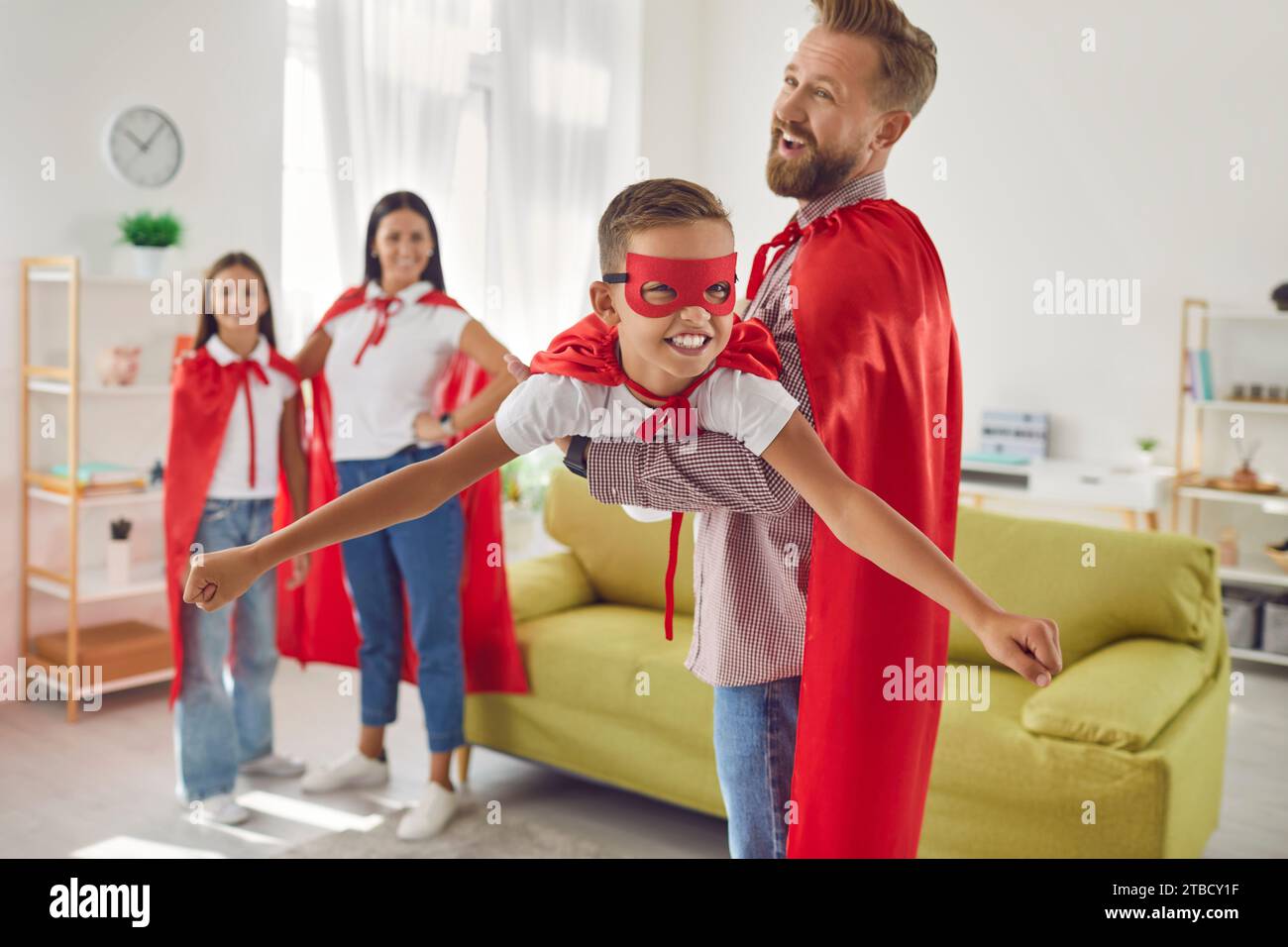 Happy smiling family of four in red super hero costumes playing game ...