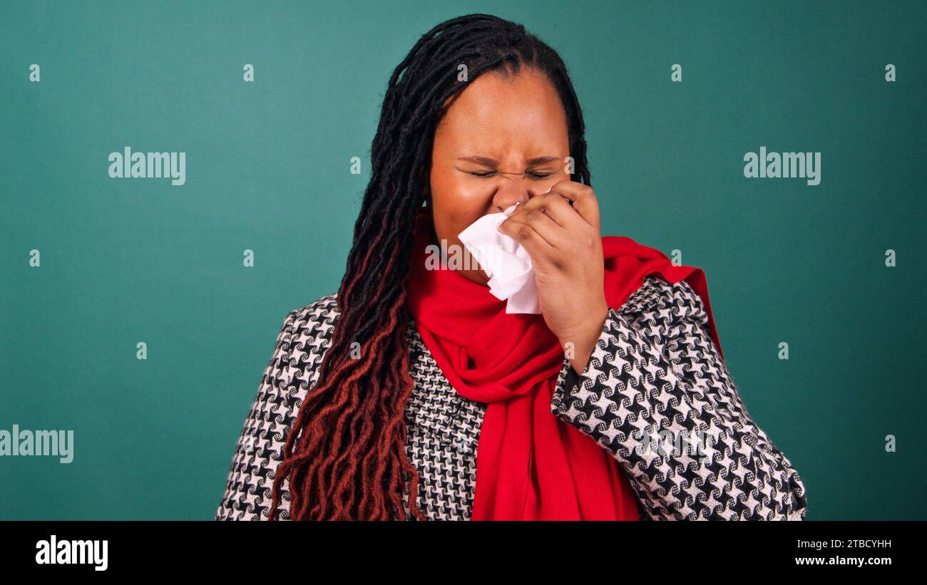 Young Black woman sneezes into tissue, blows nose, sick over Christmas ...
