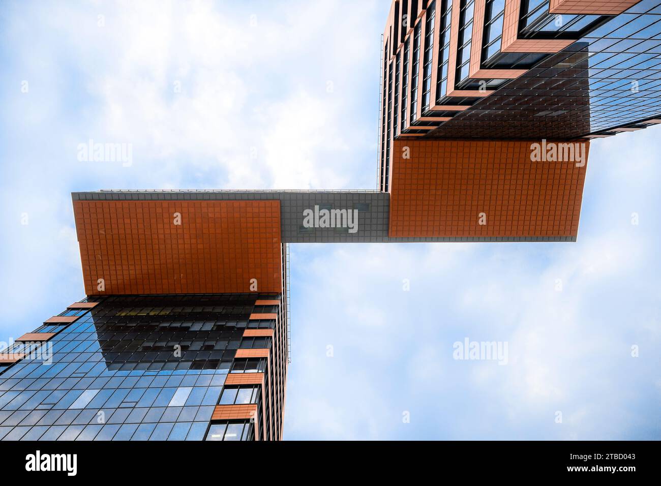 A view from below of tall office building towers connected at the top ...