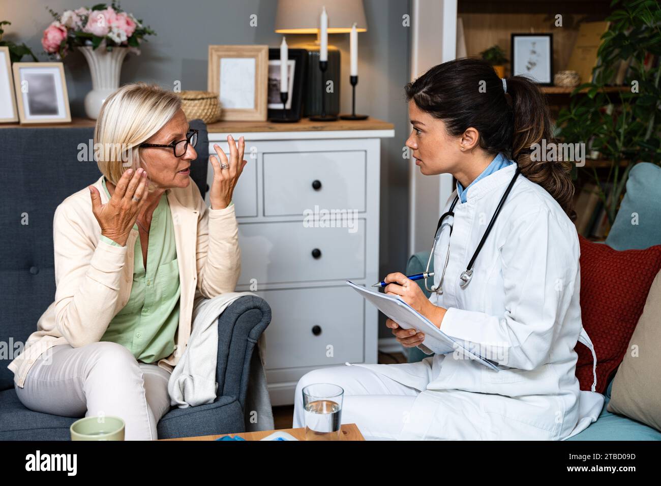 Young woman nurse doctor gp holding stethoscope examining old senior ...