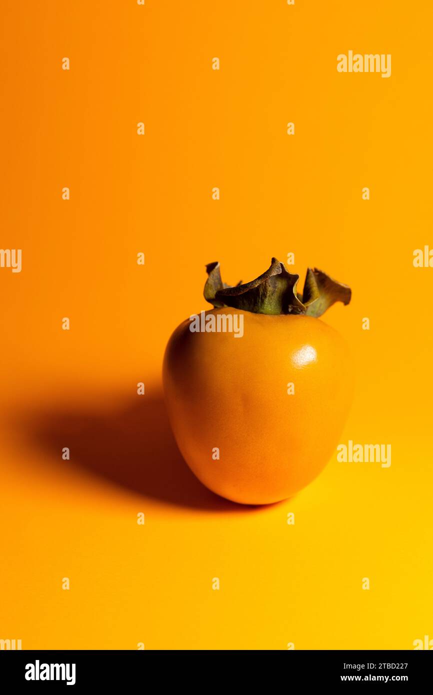 Orange persimmon fruit on an orange background Stock Photo - Alamy