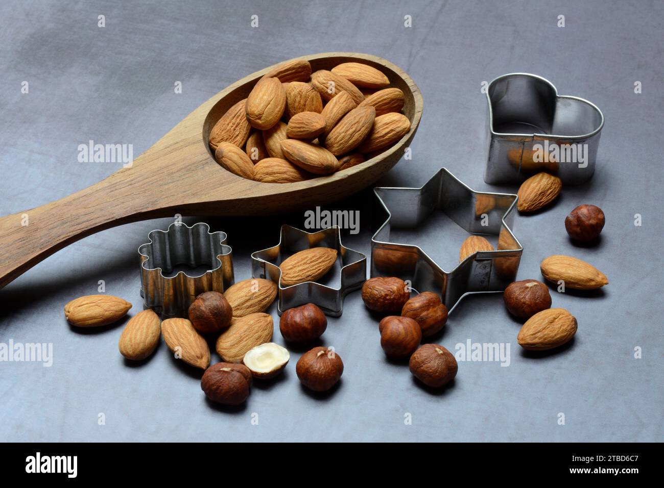 Wooden ladle with almonds and hazelnuts, cookie cutters, baking ...