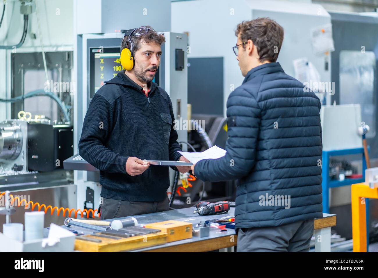 Two engineers talking while examining pieces in a cnc factory Stock ...