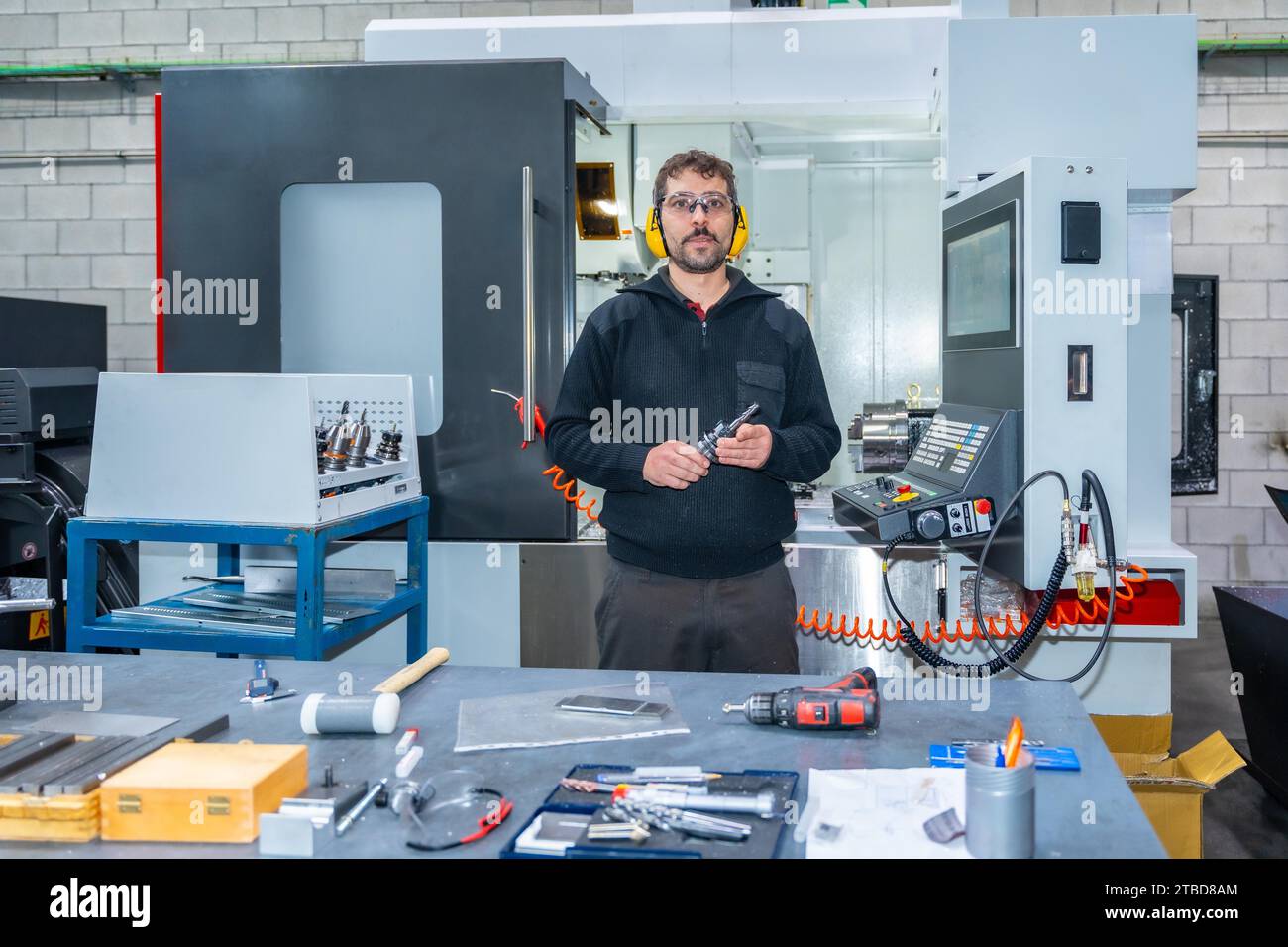 Portrait of a male engineer with safety gear working on a cnc modern ...