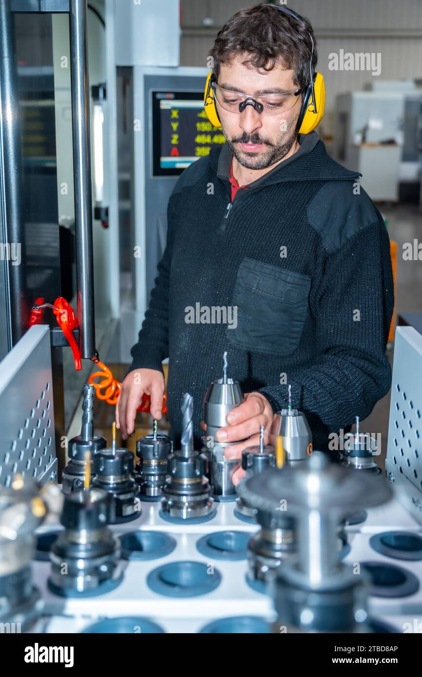 Vertical photo of a worker choosing the size of a lathe to work in a ...