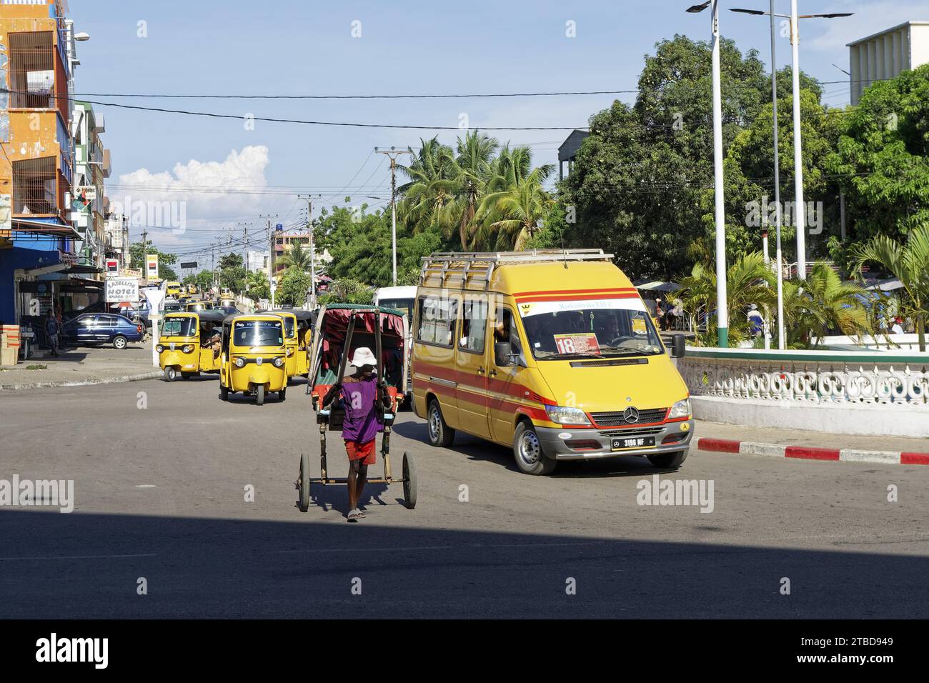 Road traffic with rickshaws, yellow tuktuks and buses, Mahajanga ...