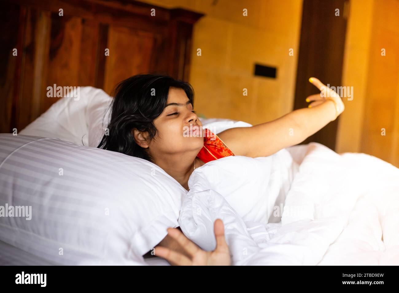 A young Indian pretty woman waking up and yawning in the morning on a ...