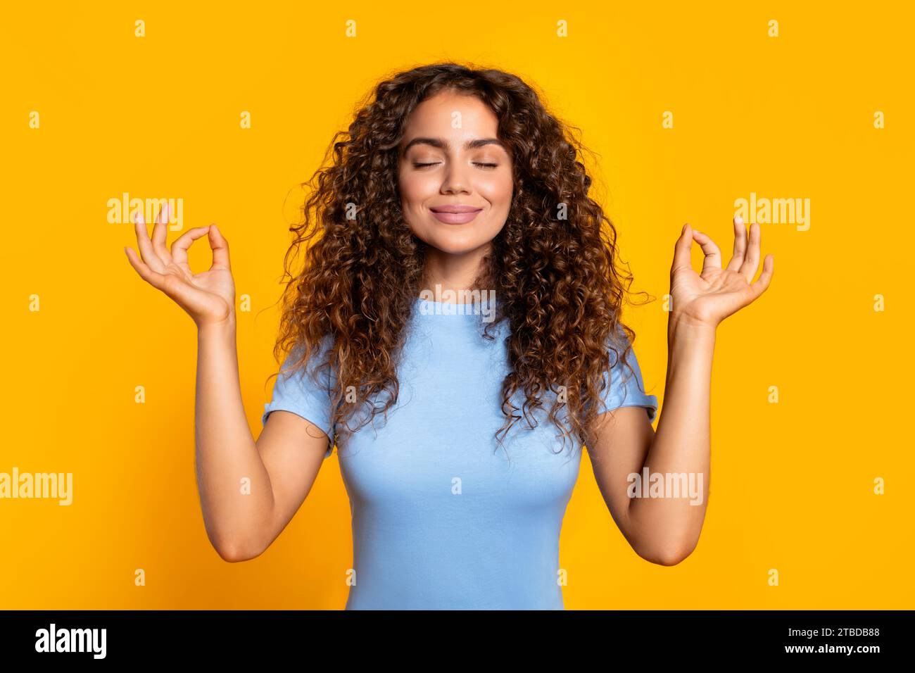 Relaxed woman meditating with hand gestures on yellow Stock Photo - Alamy