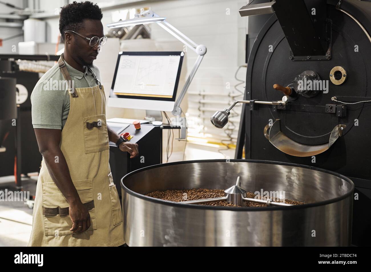 Portrait of African American young man watching coffee roasting process ...