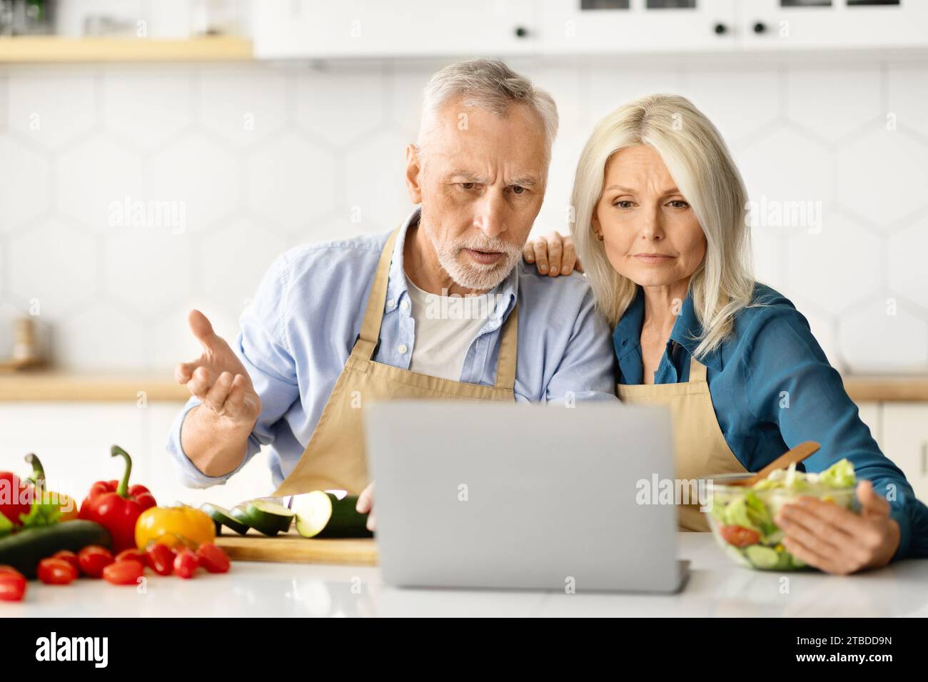Wrong Recipe. Confused Senior Spouses Looking At Laptop While Cooking ...