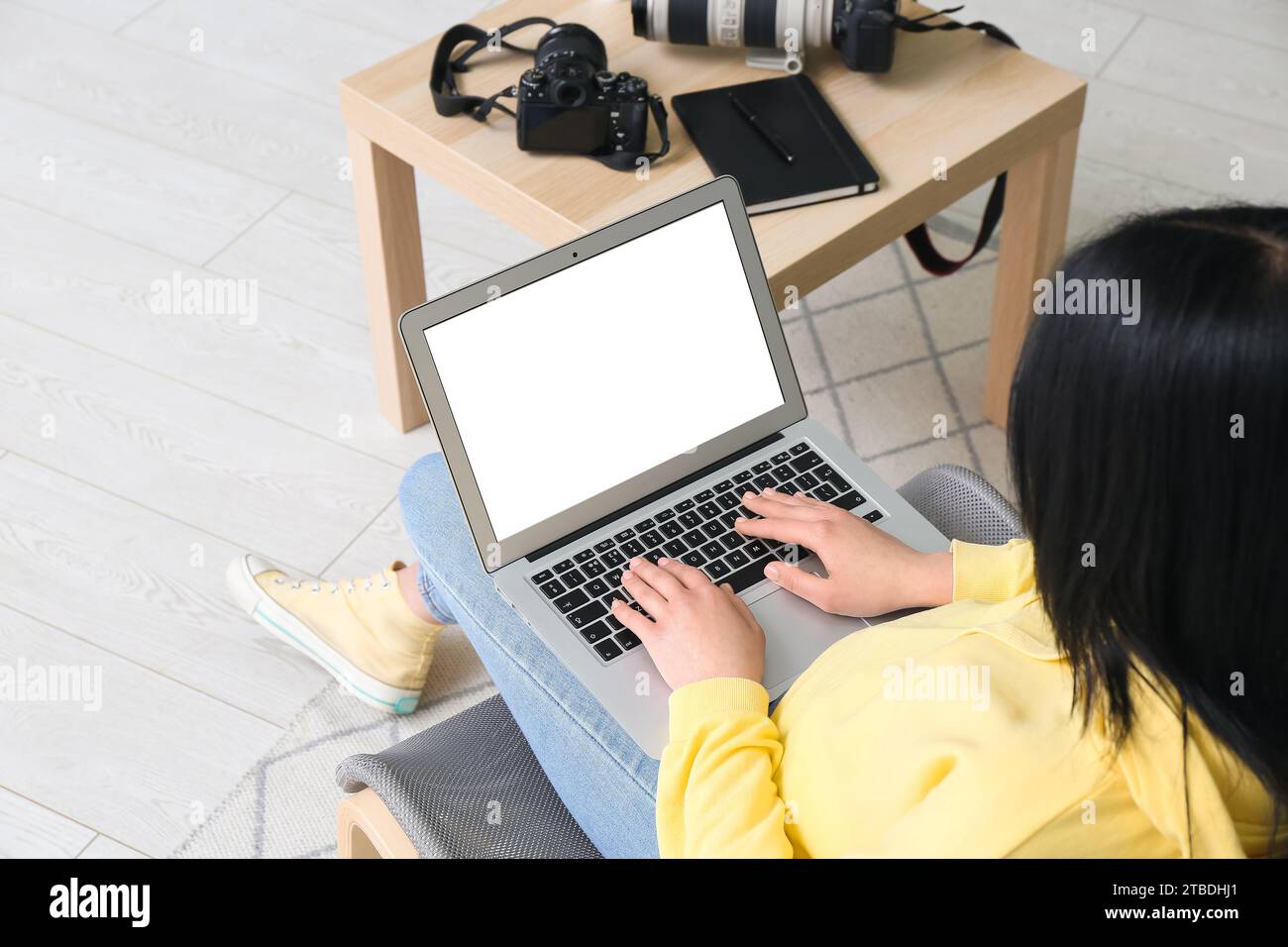 Female photographer with laptop sitting on chair Stock Photo - Alamy