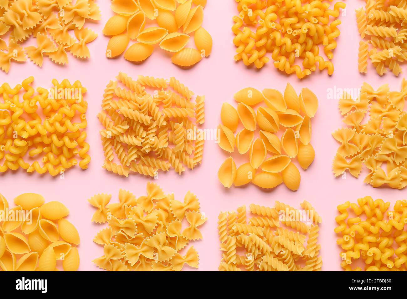 Piles of different uncooked pasta on pink background Stock Photo - Alamy