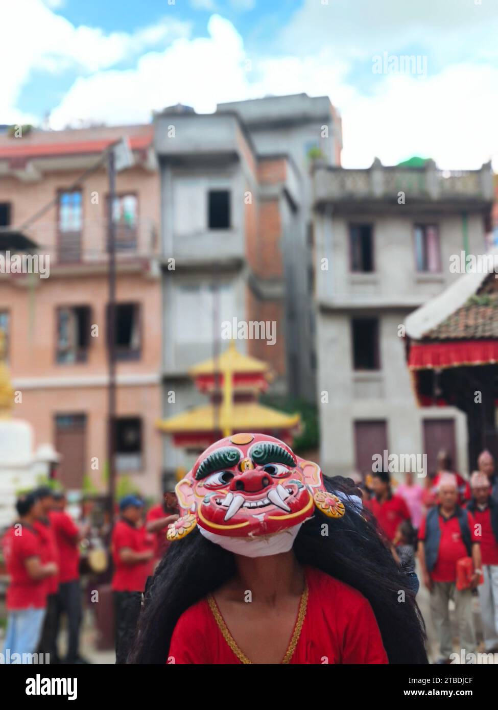 A young adult wearing a traditional mask stands amongst a group of ...