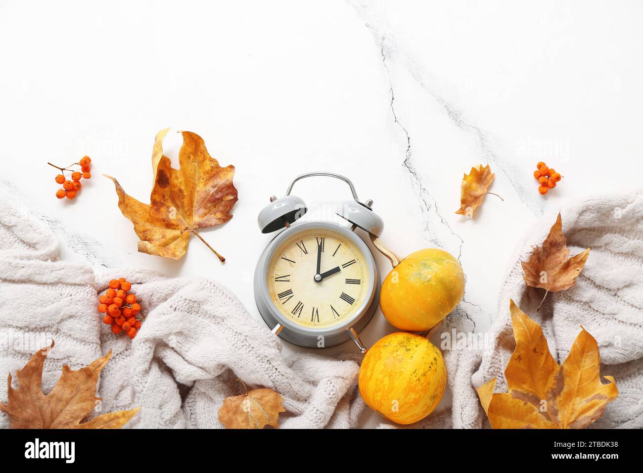 Autumn composition with alarm clock, pumpkins and leaves on white ...