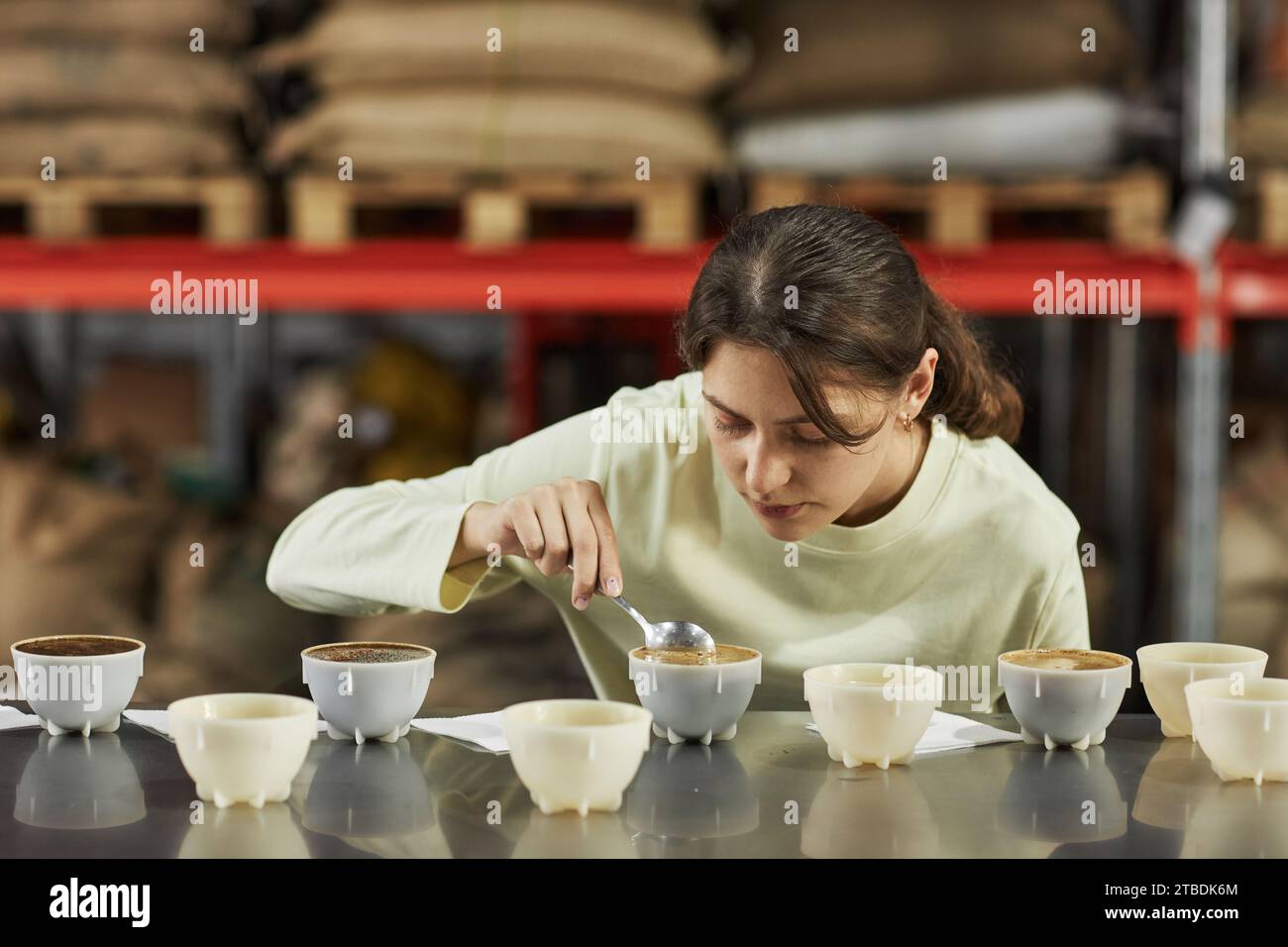 Front view of young woman breaking coffee crust and releasing aroma ...