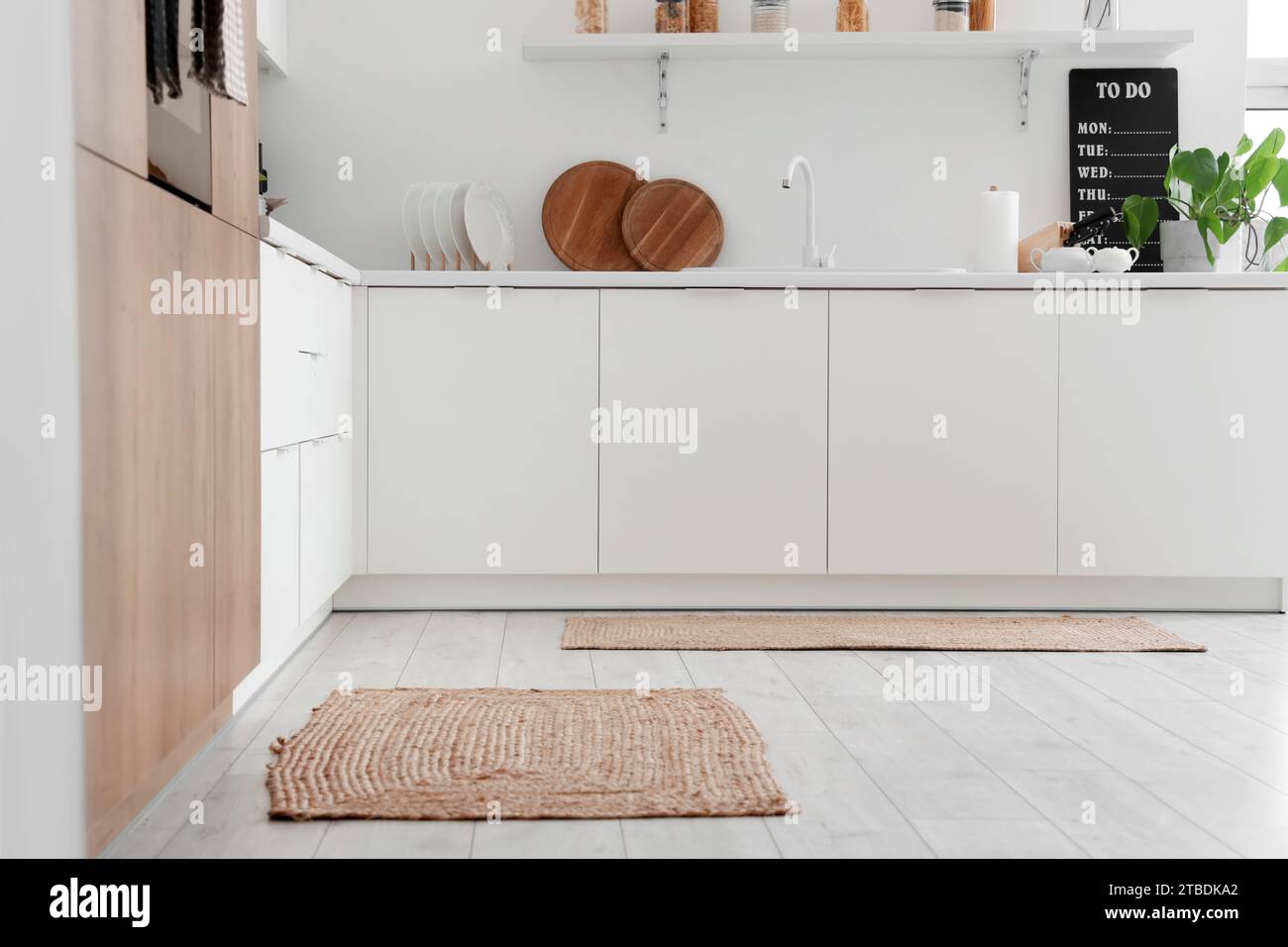 Interior of light kitchen with counters and wicker carpets Stock Photo ...