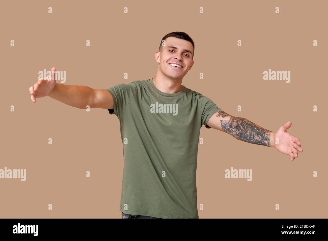 Handsome young man opening arms for hug on beige background Stock Photo ...