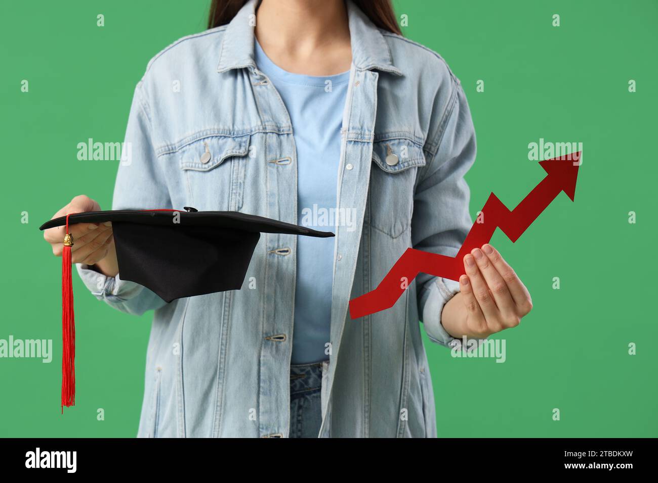 Young woman with graduation hat and arrow on green background, closeup ...