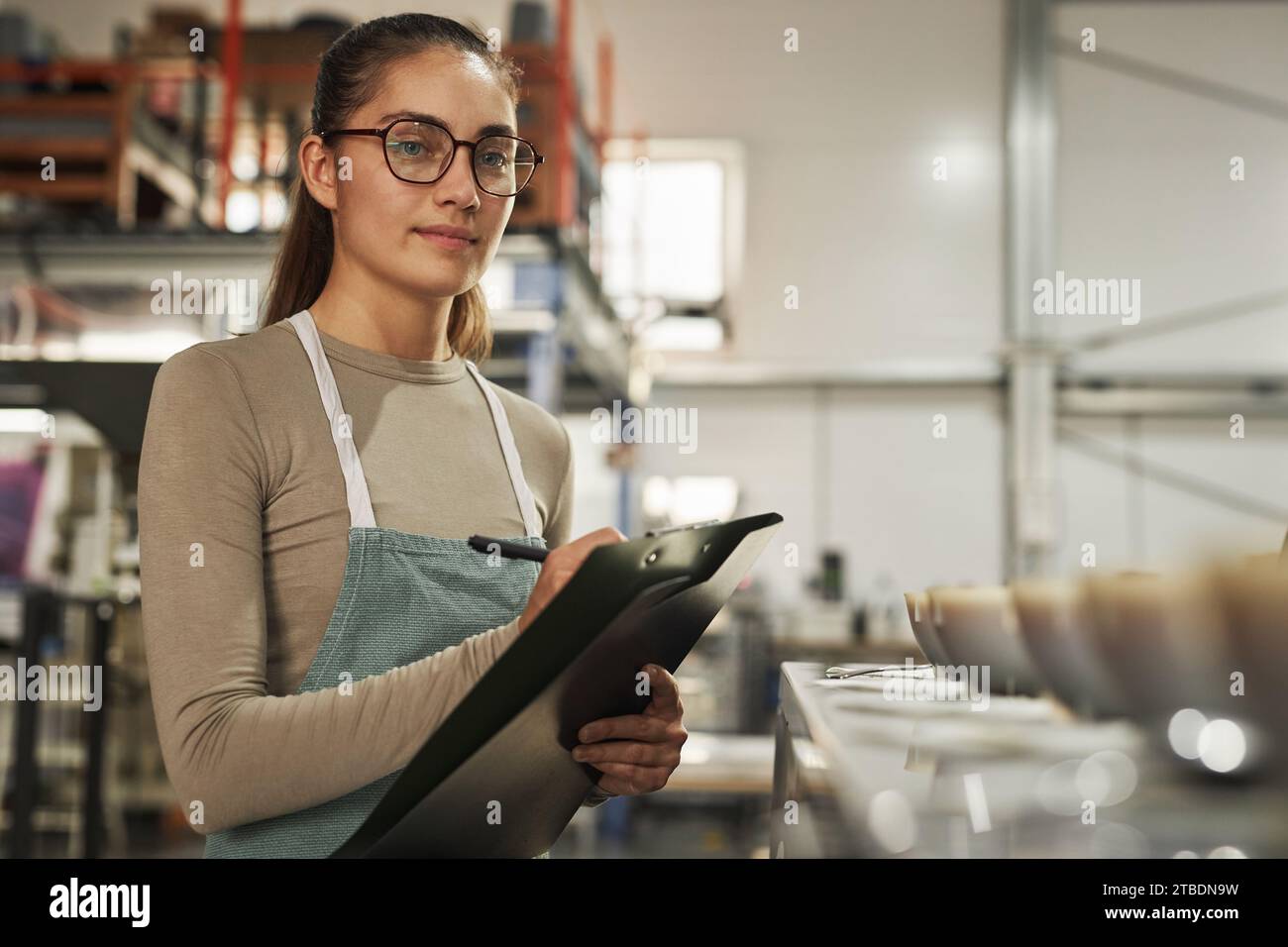 Waist up portrait of young woman as coffee expert taking notes on ...